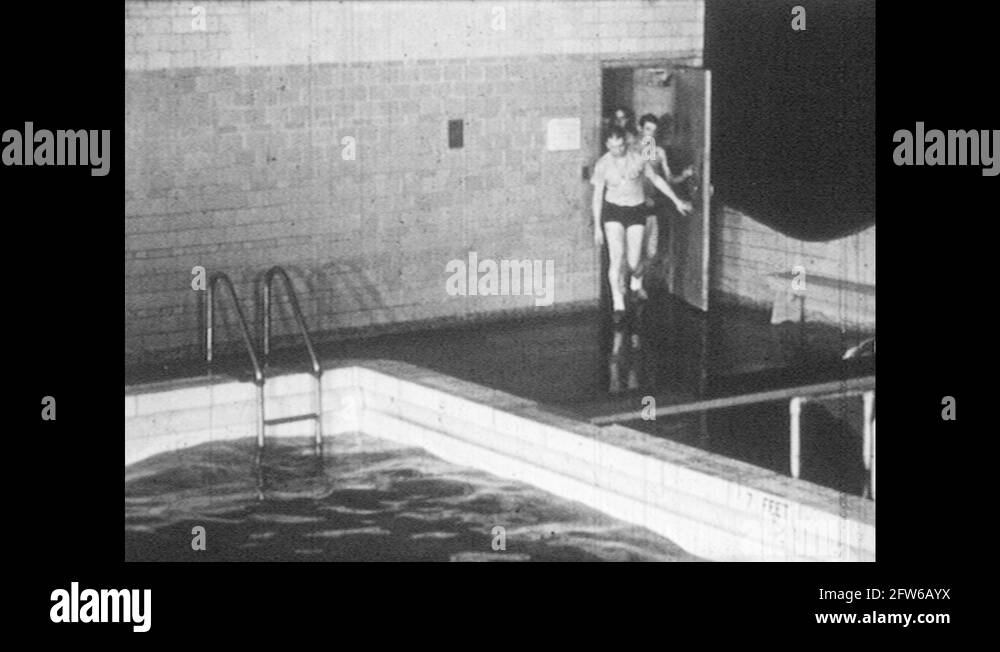 1950s: A dozen young men exit locker room wearing swimwear at indoor ...