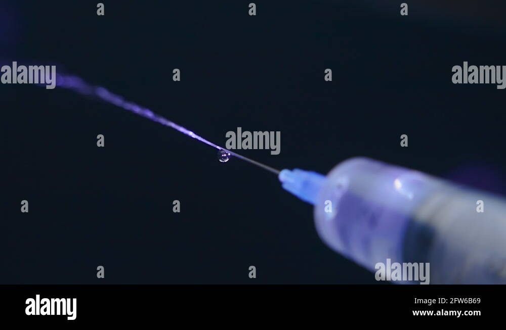 From the needle of the plastic syringe a jet of water, saline solution ...