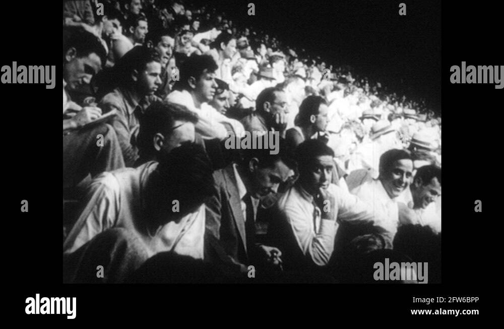 1940s: Crowd of people sitting on raised bleachers. Map of the world ...