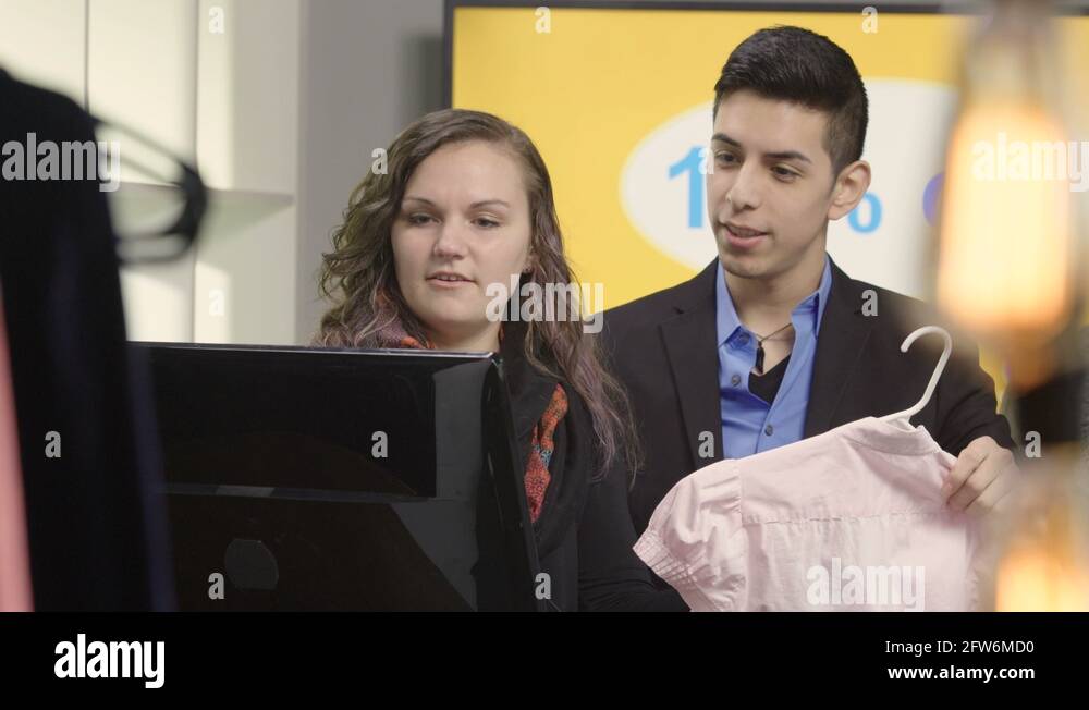 Two sales people working together behind the counter in a clothing ...