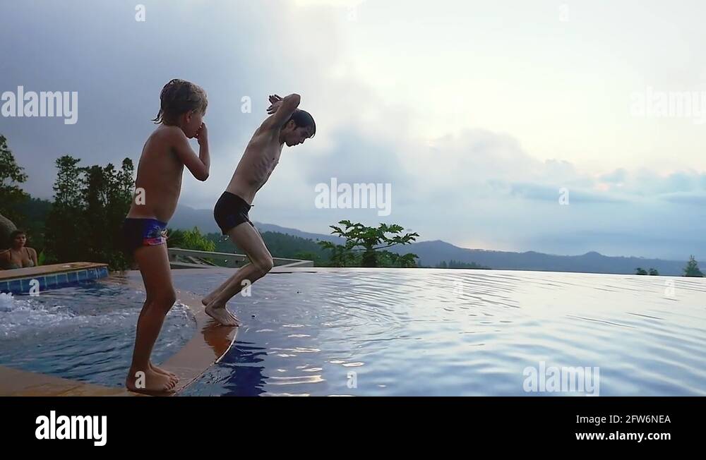 Dad and his son jumping in the pool in slow motion with beautiful ...
