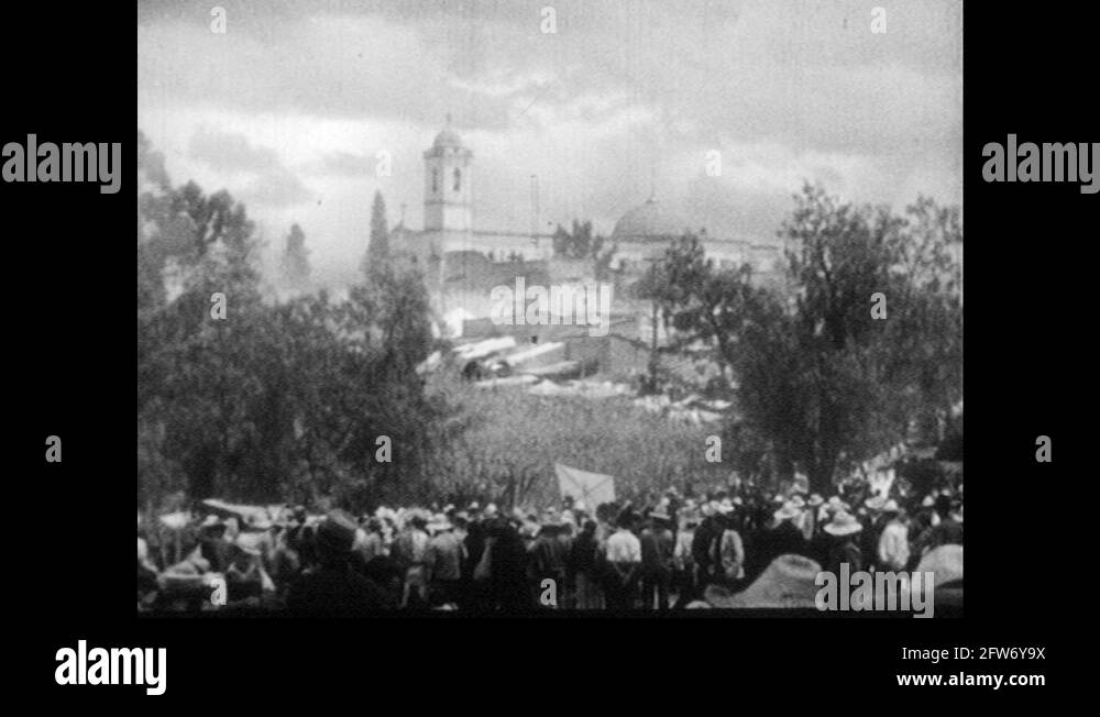 1930s: Crowd of people in village. Family travels across field. People ...