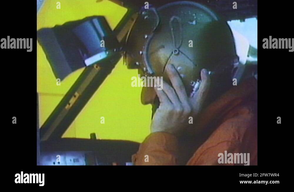 1960s: Pilot sits in cockpit of aircraft, puts on helmet, pulls down ...