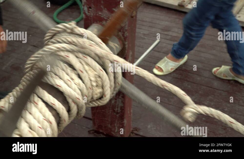 Fishermen by the tourist boat pull out an anchor. Men wind an anchor ...