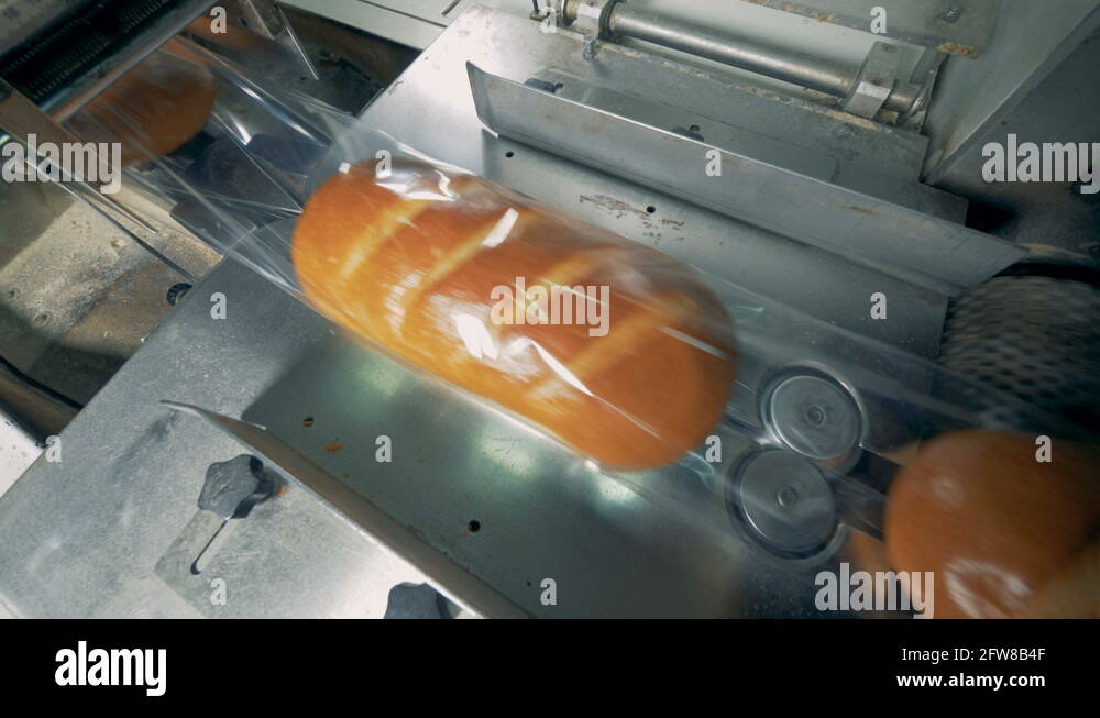 A top view on white bread loaves moving covered with clear film Stock ...