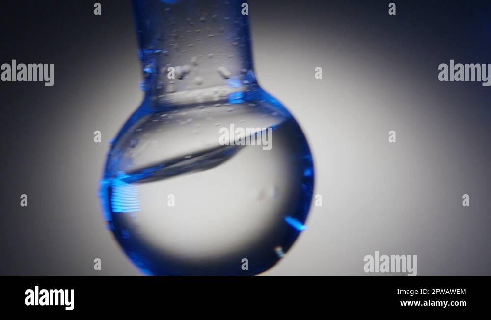 Lucid water with shining tints is shaken in a round flask in a chemical ...