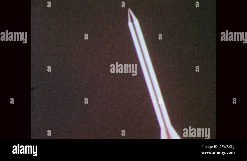 1960s: Model rocket ship flies through sky. Smoke and fire billows from ...