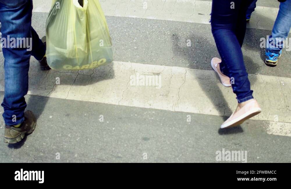 People walk across a busy crosswalk at a city intersection with the ...