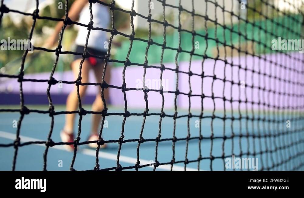 Girl playing tennis, view with blur from the grid. Slow motion. HD ...