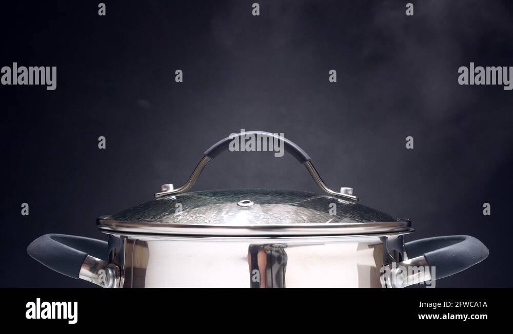 The cook opens the lid of the pan and salt the soup. The chef at the ...