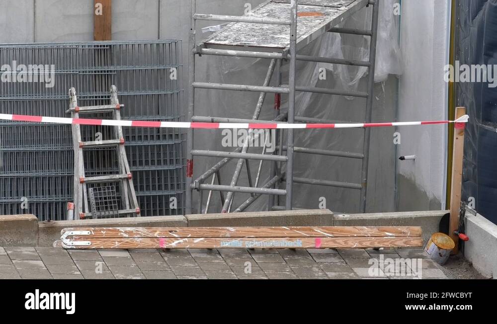 Tilt: scaffold, ladders, steel fence next to newly built house ...