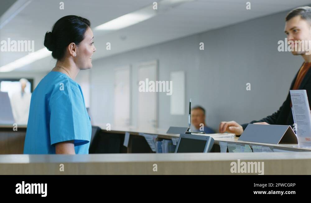 In the Hospital at the Reception Desk Nurse on Duty Talks With Patients ...
