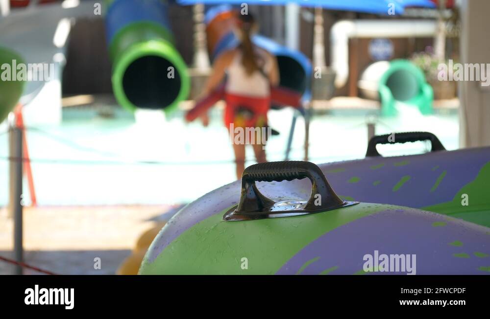 Boys walking in a water park carrying an inner tube by water slides ...