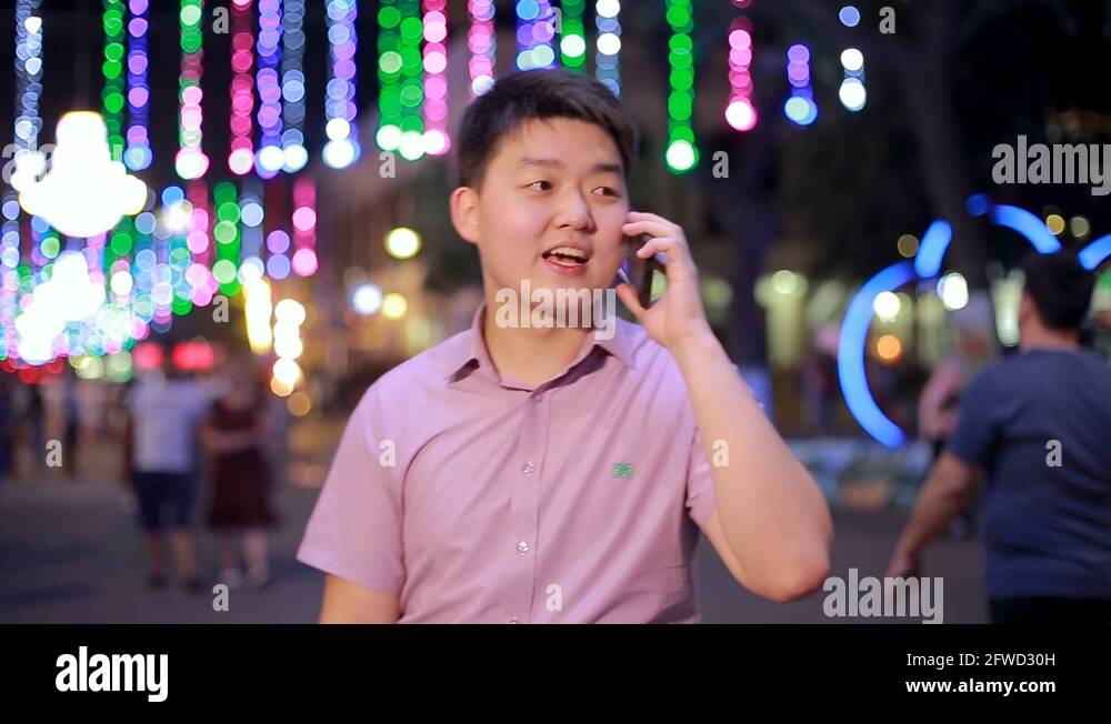 Asian boy talking at night in the Park, where a lot of lights ...