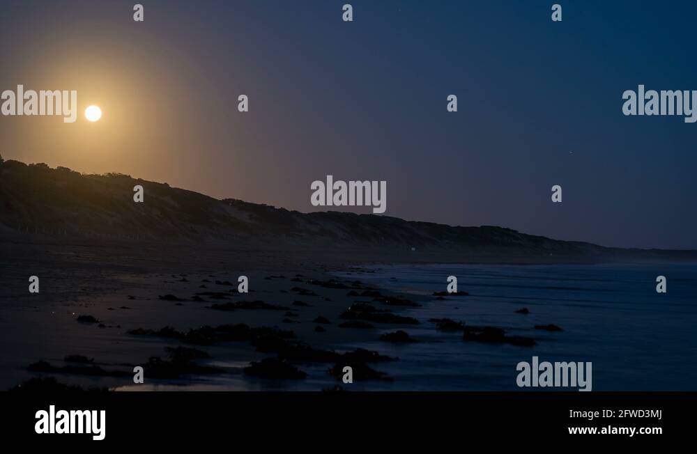 Time lapse of the full moon rising over a beautiful beach at night on ...