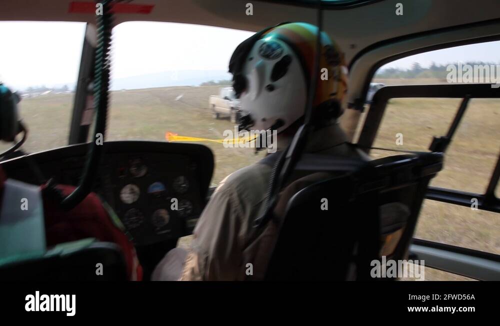 Interior view of chopper taking off with pilot with white helmet and ...