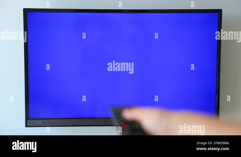 black modern tv set with blank blue screen and hand holding remote ...