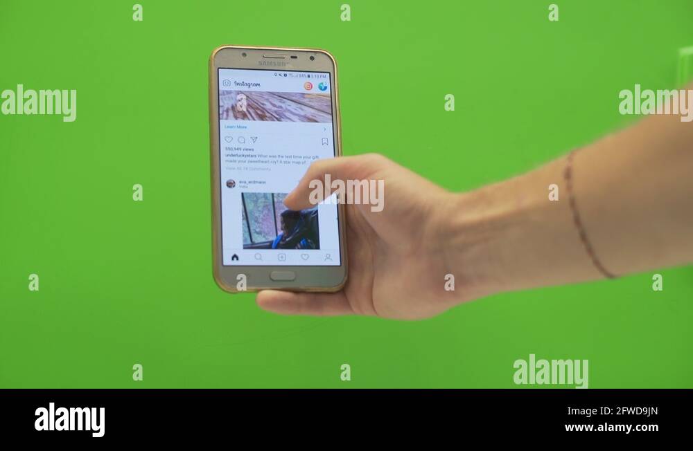 A caucasian hand scrolling through the instagram social media platform ...