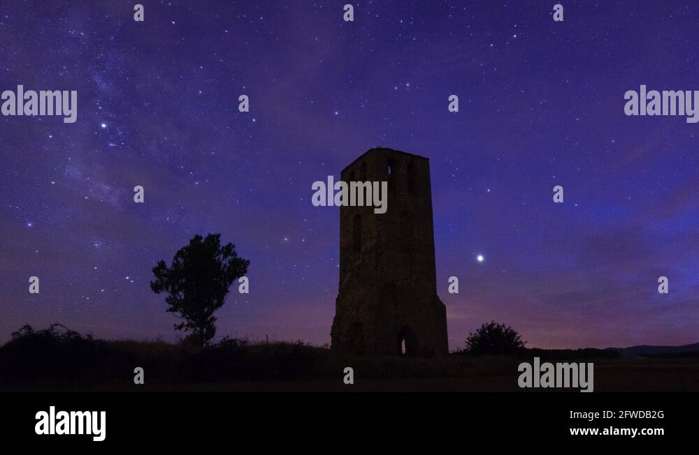 The Milky Way moving across the night sky and an ancient castle tower ...