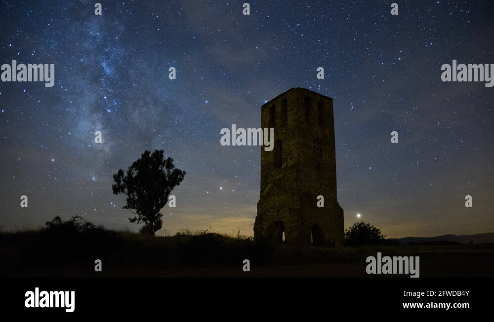 The milky way moving across the night sky and an ancient castle tower ...