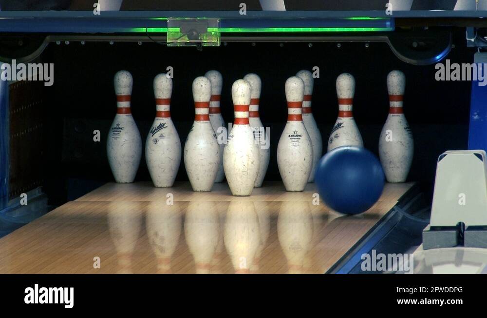 A blue bowling ball hits a single pin in a bowling alley before the ...