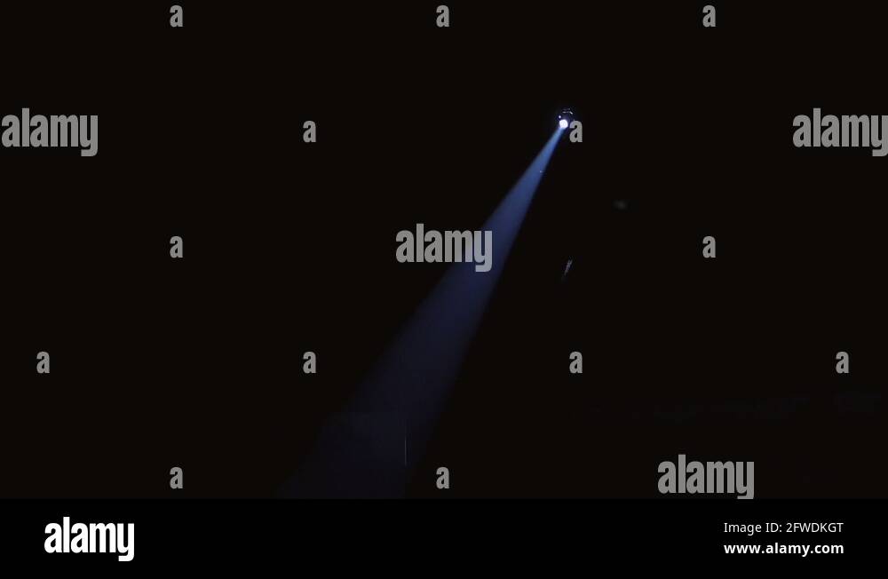 Blue light from a single spotlight through the darkness in a theater or ...