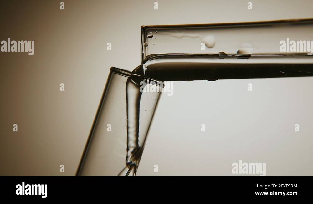 Distilling water is poured from one test tube into another in a ...