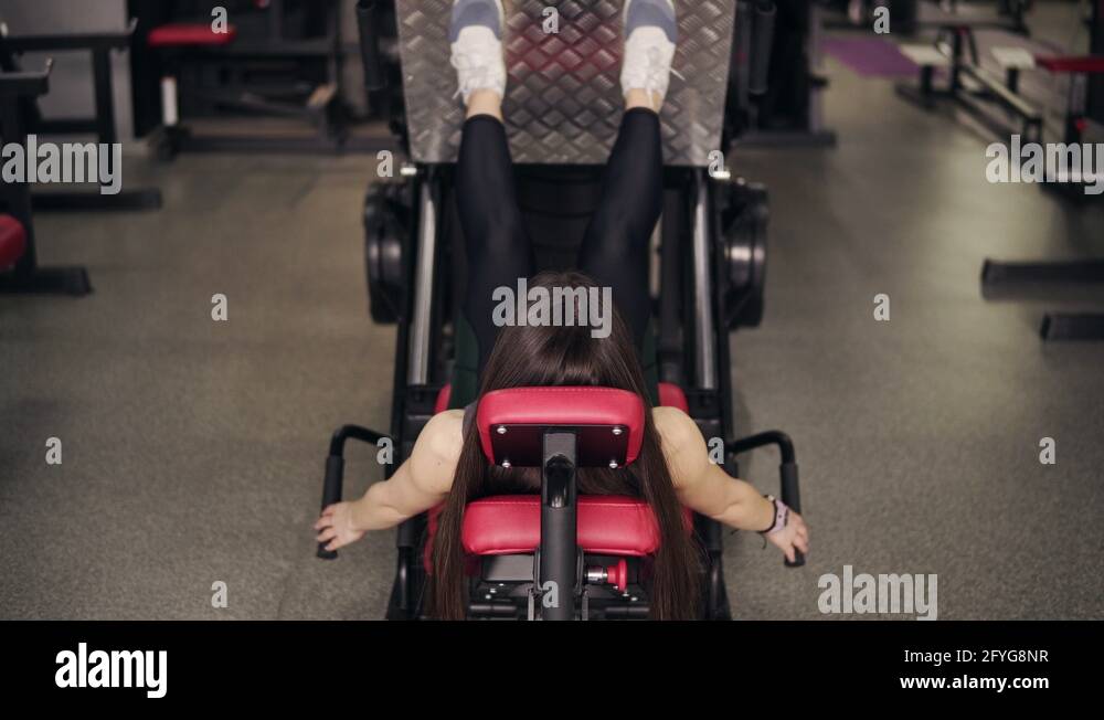 Backside footage of a sportive brunette girl working out on leg press ...