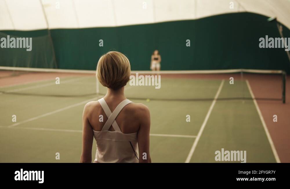 Backside slow motion footage of a female sportive tennis player hitting ...