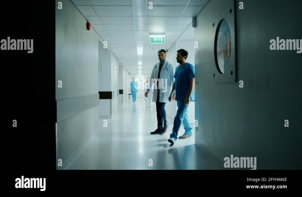 Surgeon and Doctor Walk Through Hospital Hallway in a Hurry while ...