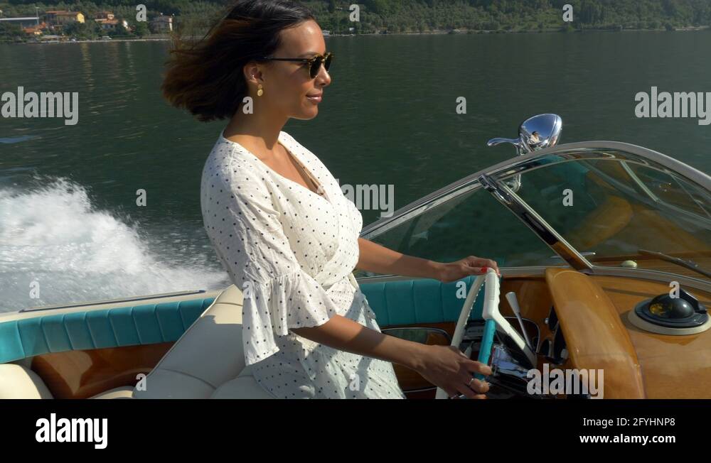 A woman on a classic luxury wooden runabout boat on an Italian lake ...