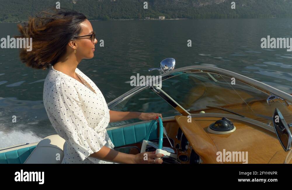 A woman on a classic luxury wooden runabout boat on an Italian lake ...