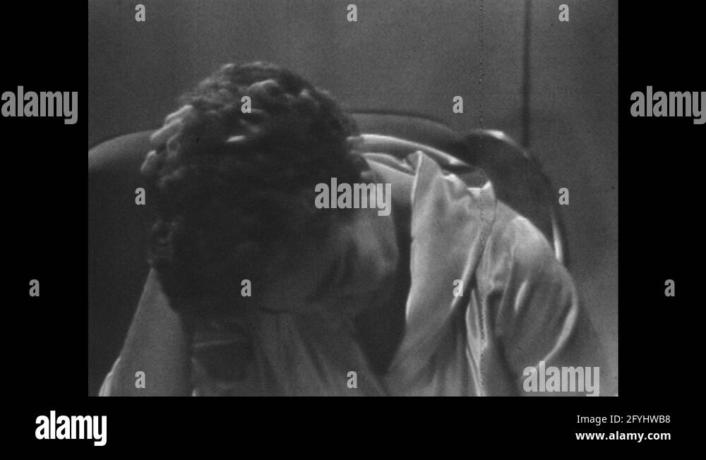 1950s: Woman sits in chair holding head in hands mournfully, then looks ...