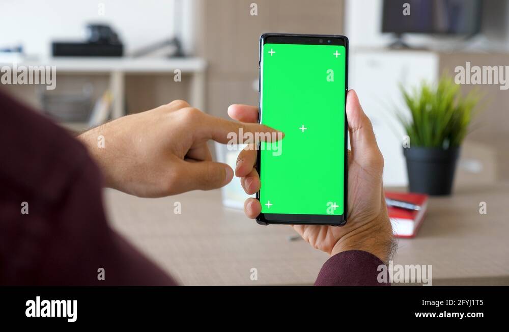 Man hand scrolling down on a smartphone with green screen chroma mock ...