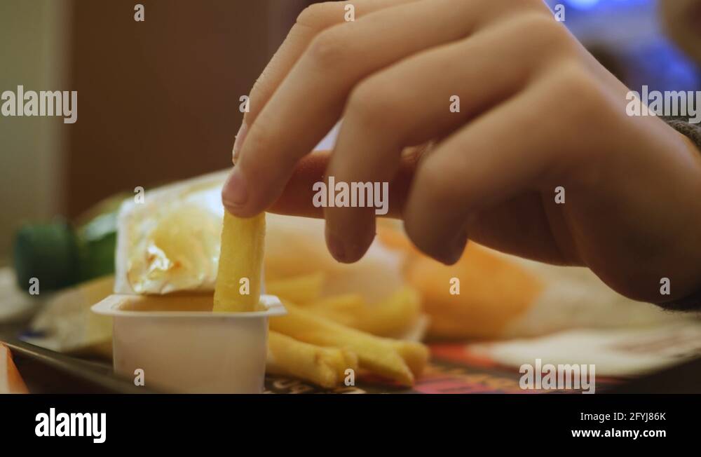 A boy in a fast food restaurant eating french fries. Fast food. Healthy ...