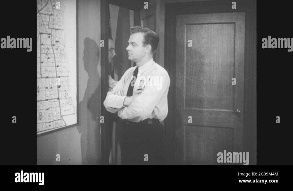 1950s: Police officer stands in front of map with folded arms. Sergeant ...