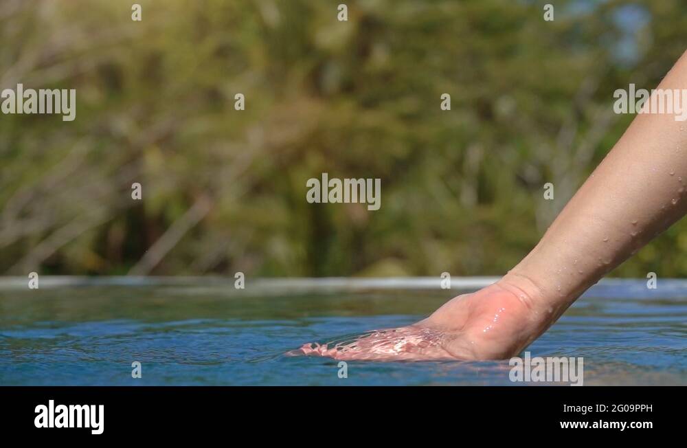 SLOW MOTION Detail of a hand scooping and pouring water on swimming ...