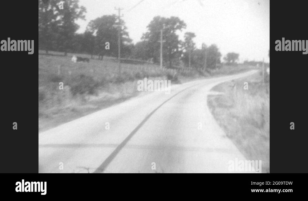 1920s: UNITED STATES: view through vehicle window of country road ...