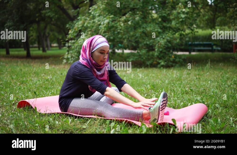 A Muslim woman in a burqa doing exercises for stretching the muscles of ...