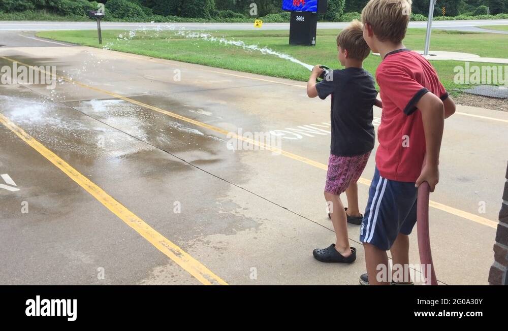 Boys playing with fire hose at fire station pretending to be fireman ...