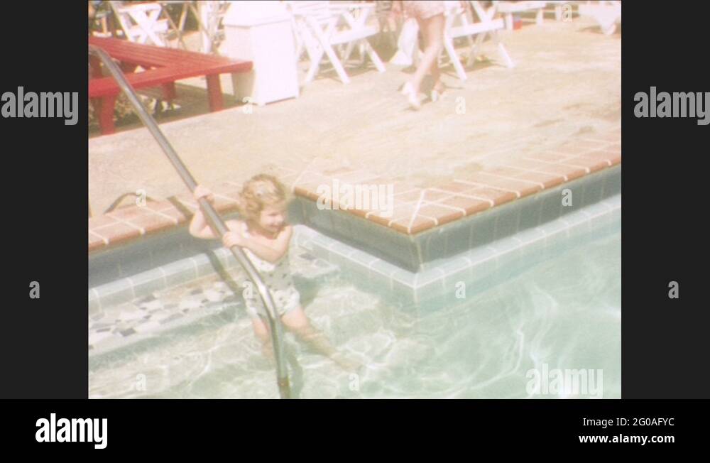 1940s: Young girl goes in pool. Children hold hands and play on beach ...