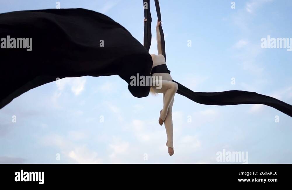 Girl dancing with aerial silk flying wings in sky background rapid slow ...