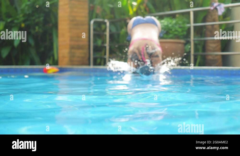 Young woman jumping swimming and swims up, out of pool in slow motion ...