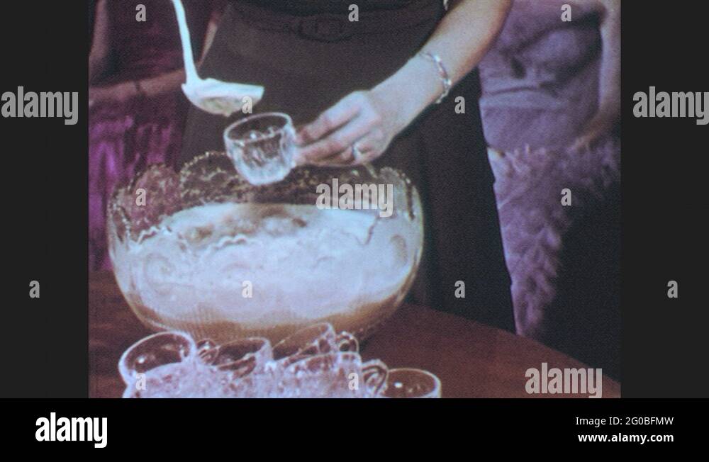 1950s: Woman spoons punch from bowl. Boy carries punch to seated girl ...