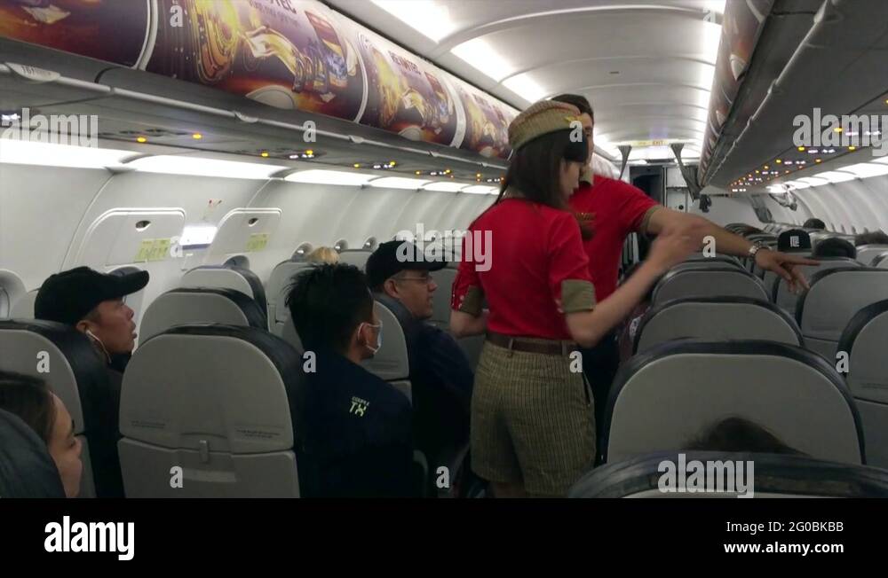 Vietnamese cabin crew Vietjet Air in uniform go along aisle between ...