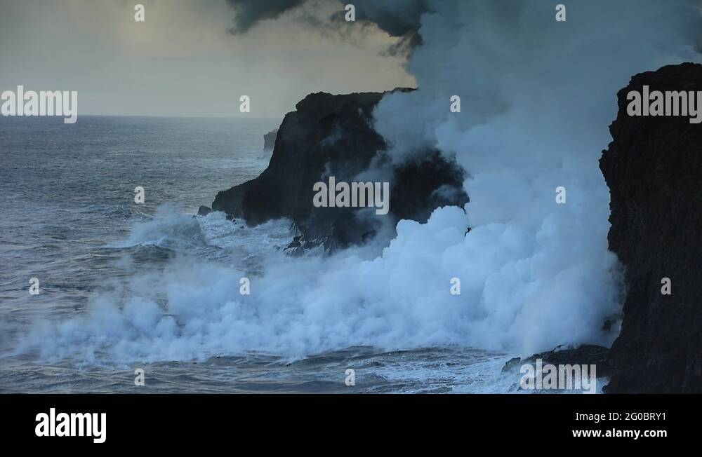 Lava flows after sunset into the ocean, steam cloud rising from water ...