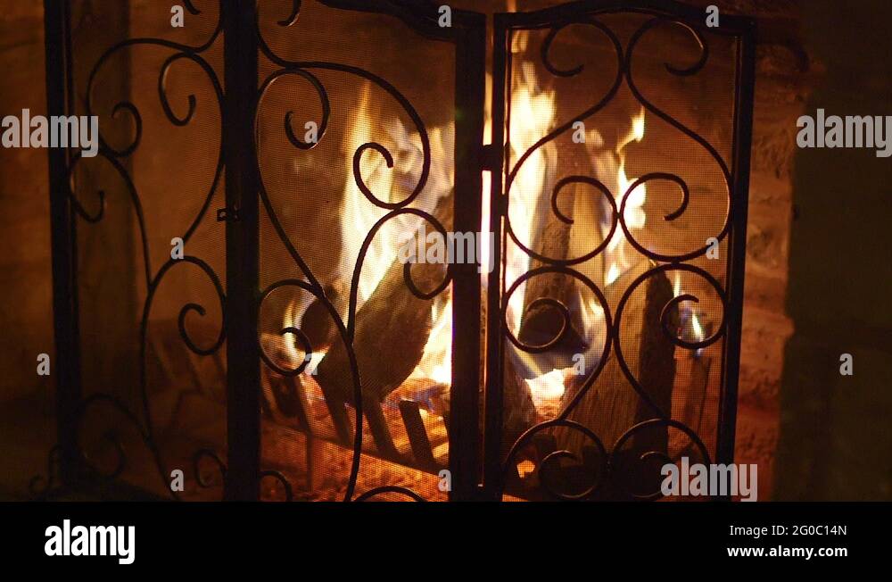 Logs Burning in Vintage Stone Fireplace with Decorative Screen and ...