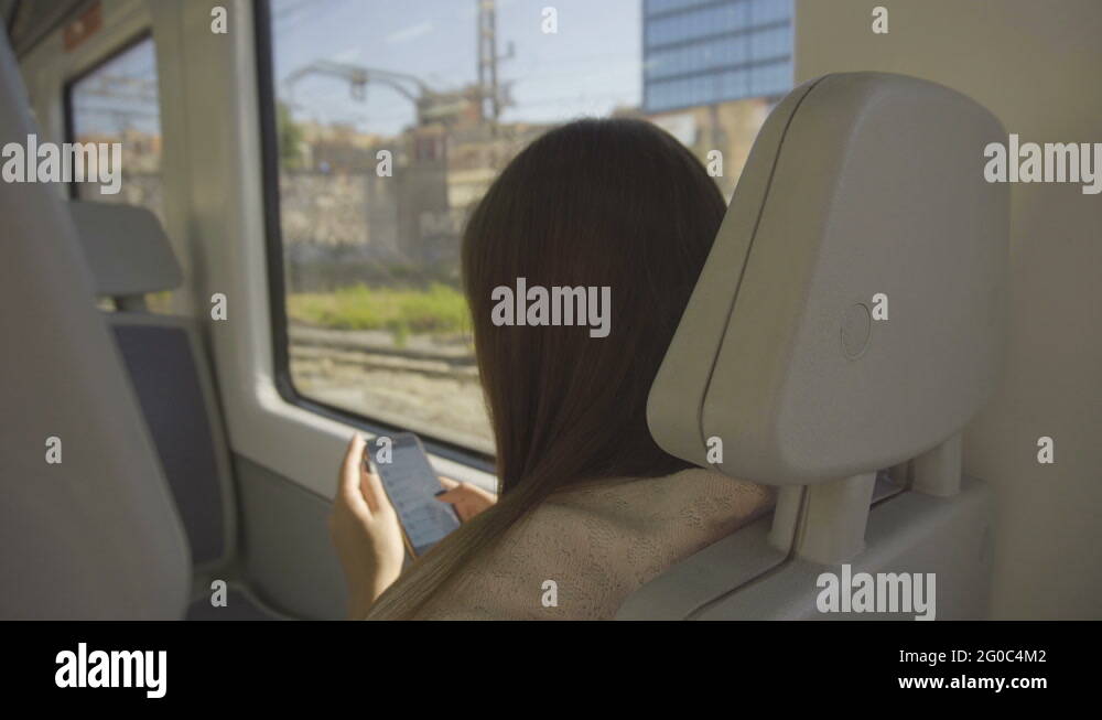 Beautiful young girl seats in the wagon of the train and use the ...
