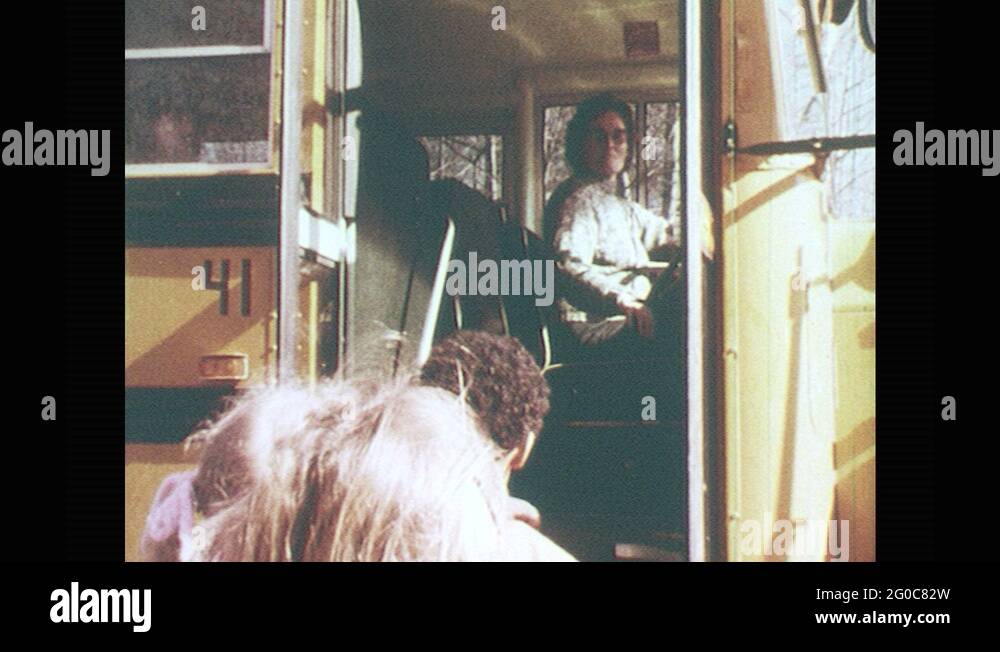 1970s: Children board school bus, bus driver woman speaks. Girl in fur ...