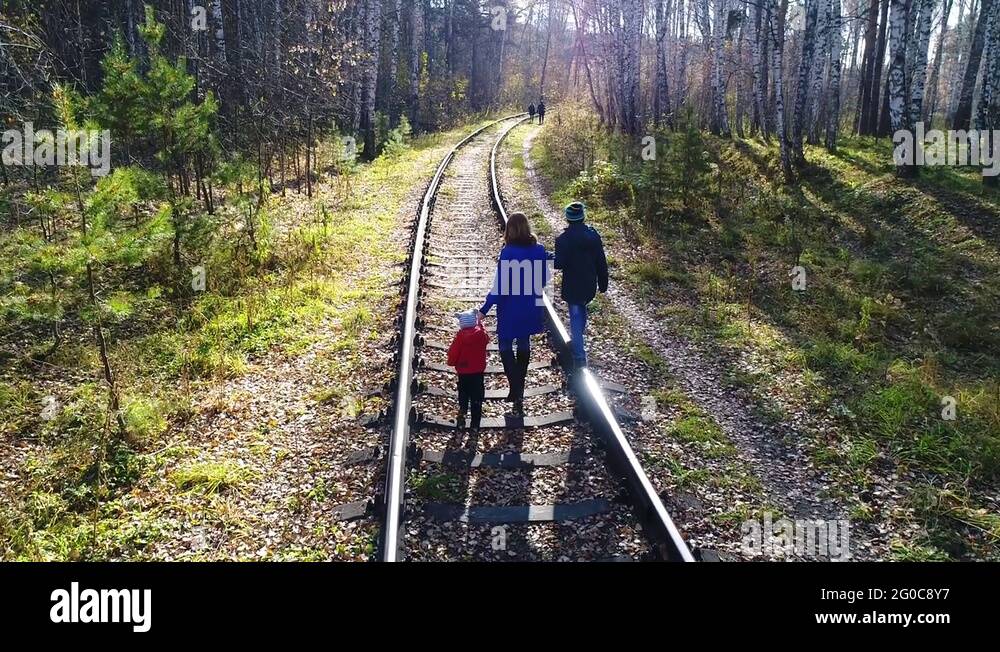 A young girl with two children walking on the railroad. A walk outdoors ...